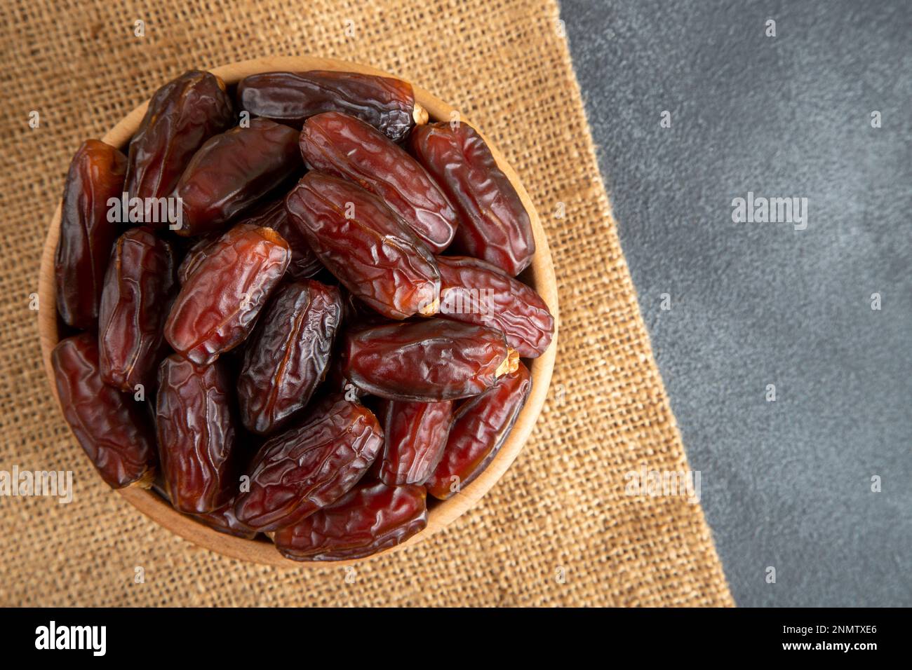 Date fruits in wooden bowl on black background,top view Stock Photo - Alamy