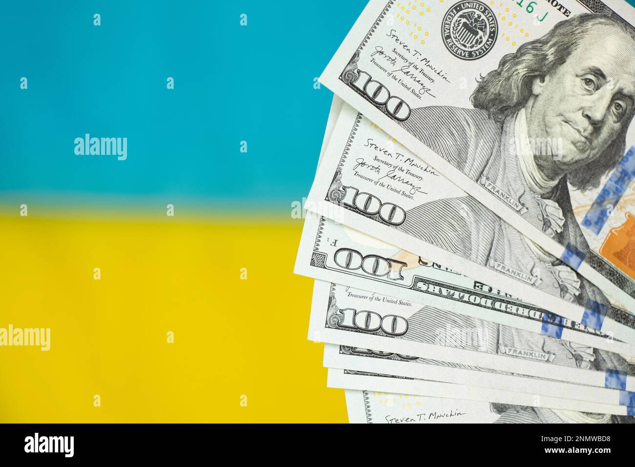 Hundred dollar bills against the background of the flag of Ukraine ...