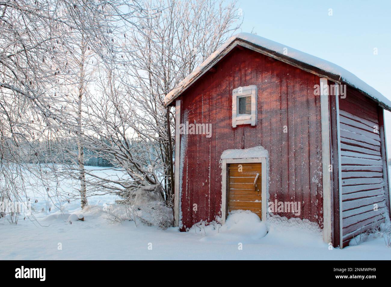 A traditional red Finnish barn in winter, covered in frost and snow ...