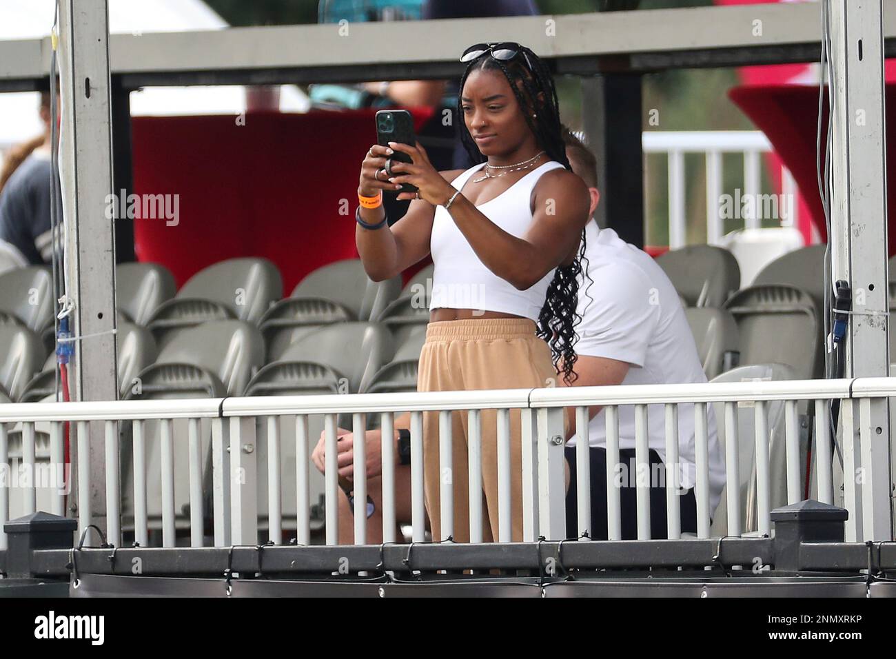 Olympic gymnast Simone Biles takes photos with her phone as she watches ...