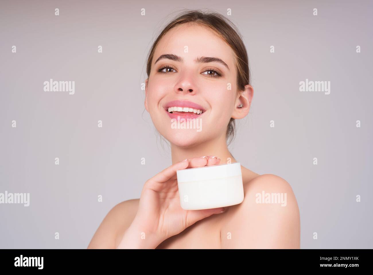 Skin care. Beauty portrait of a beautiful woman applying face cream ...