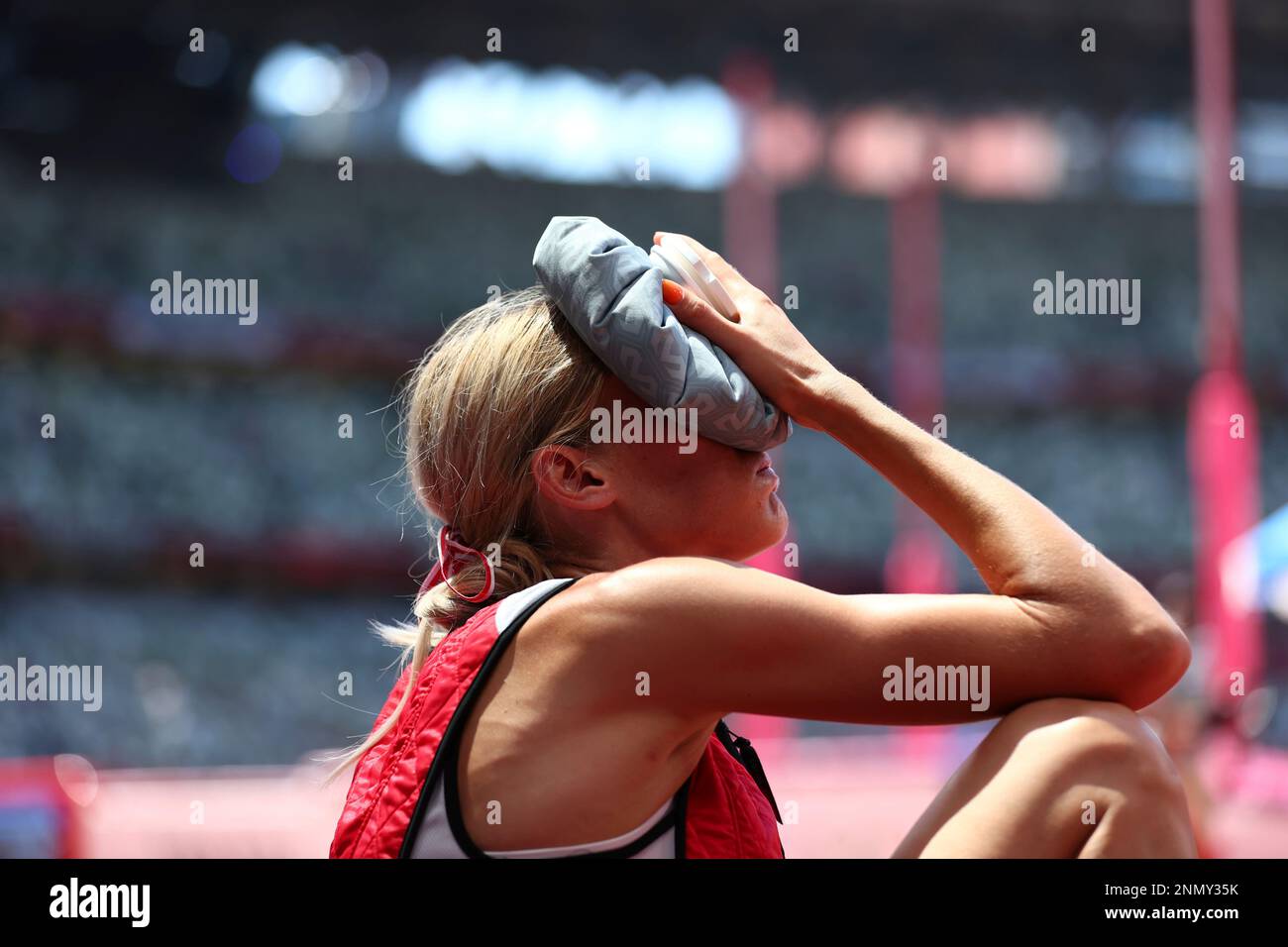 An athlete puts an icing on her head under a hot day to cool down at ...