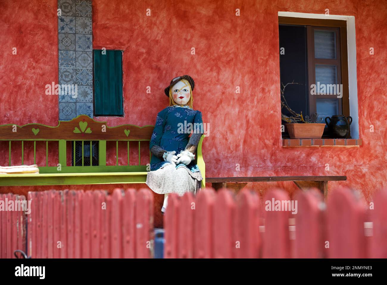 Full-size doll on a bench against red wall, old german country Stock ...