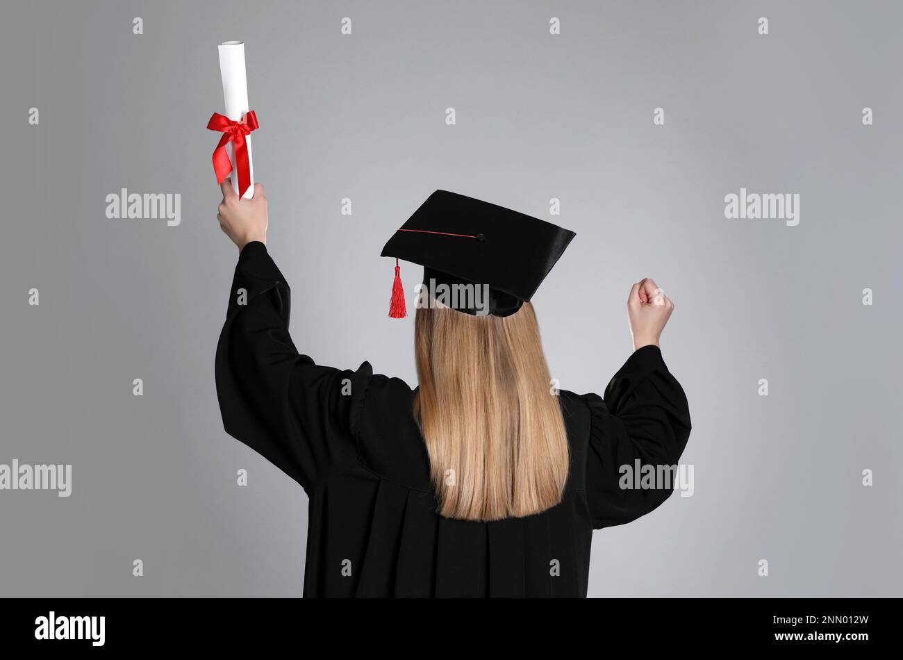 Student with diploma on grey background, back view Stock Photo - Alamy