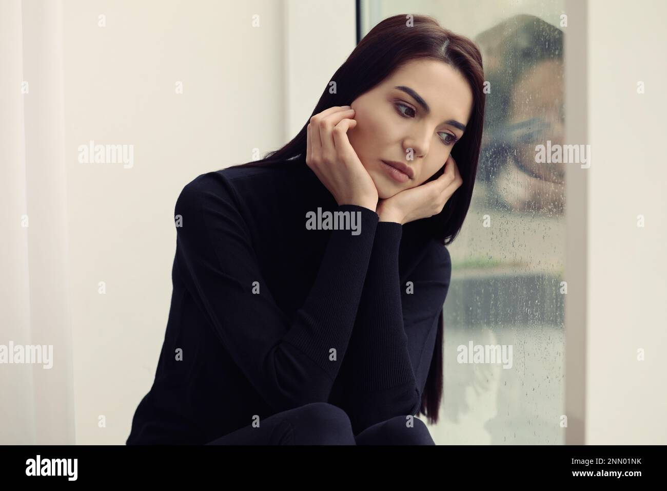 Depressed woman near window on rainy day Stock Photo - Alamy
