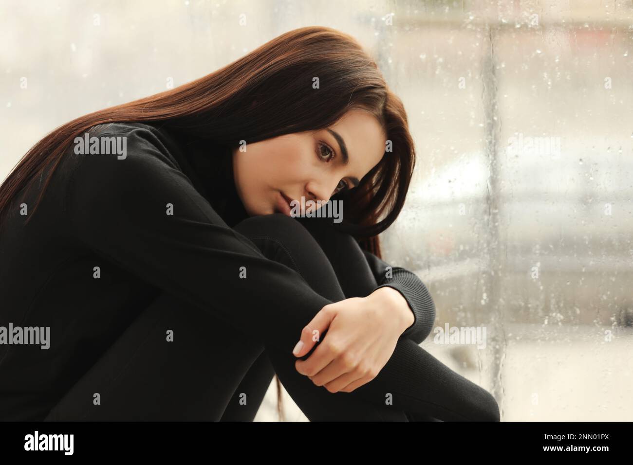 Depressed woman near window on rainy day Stock Photo - Alamy