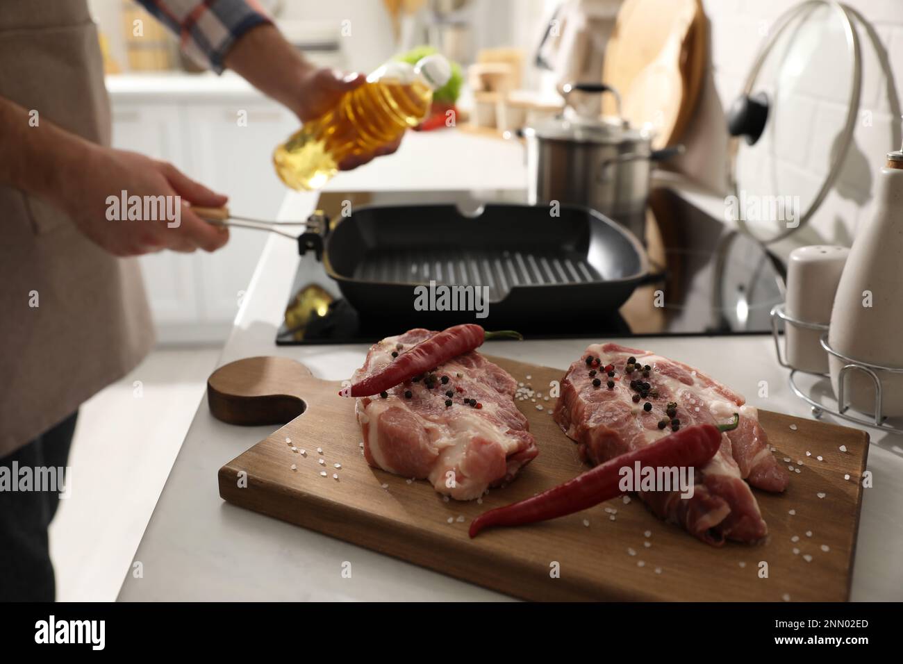 Man pouring cooking oil into frying pan, focus on raw meat Stock Photo ...