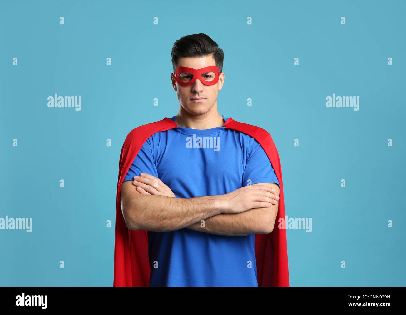 Man wearing superhero cape and mask on light blue background Stock ...