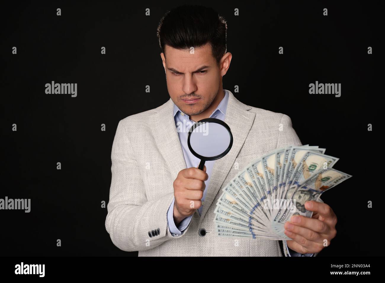 Expert authenticating 100 dollar banknotes with magnifying glass ...