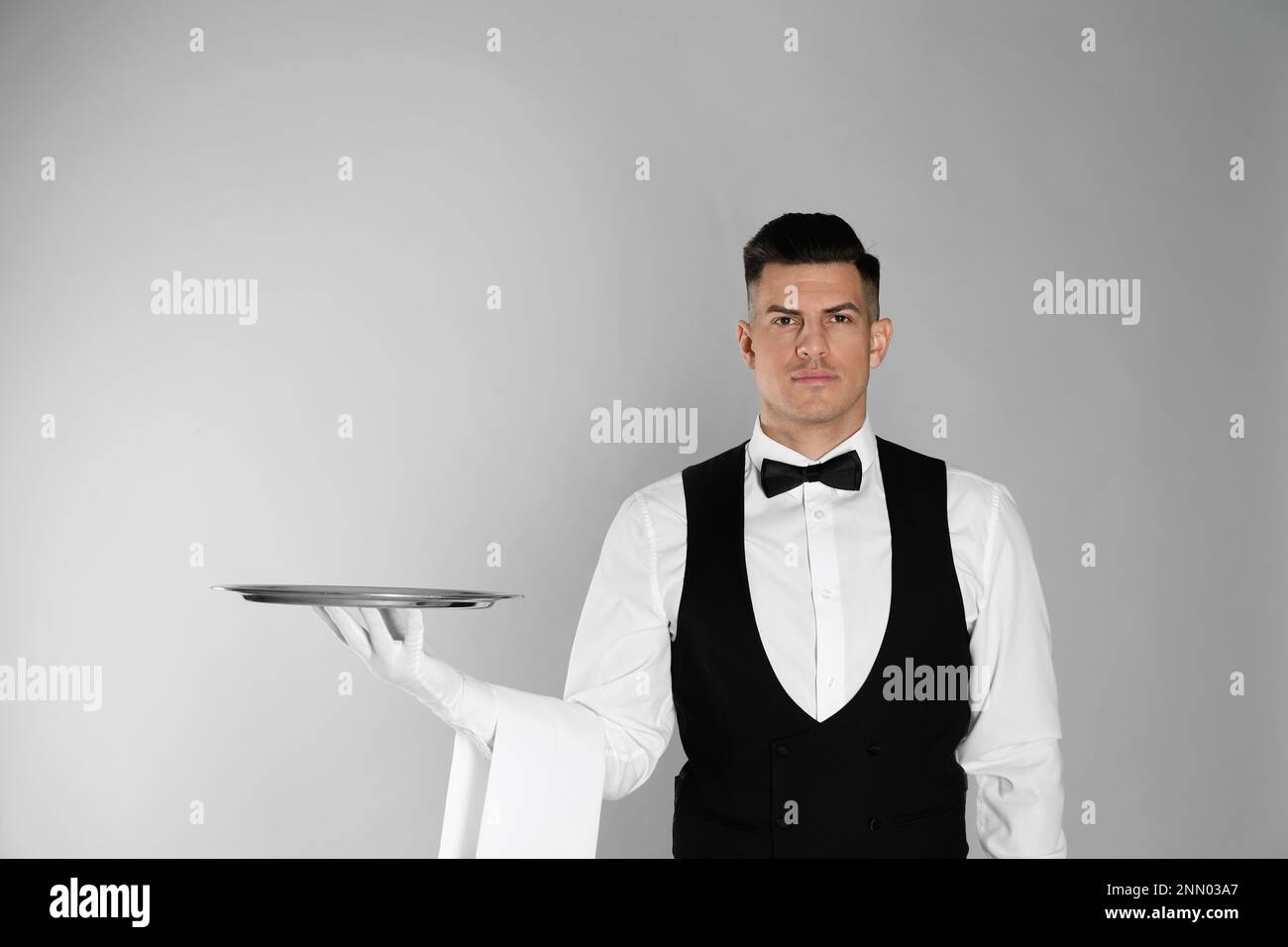 Handsome butler with tray on light grey background Stock Photo - Alamy