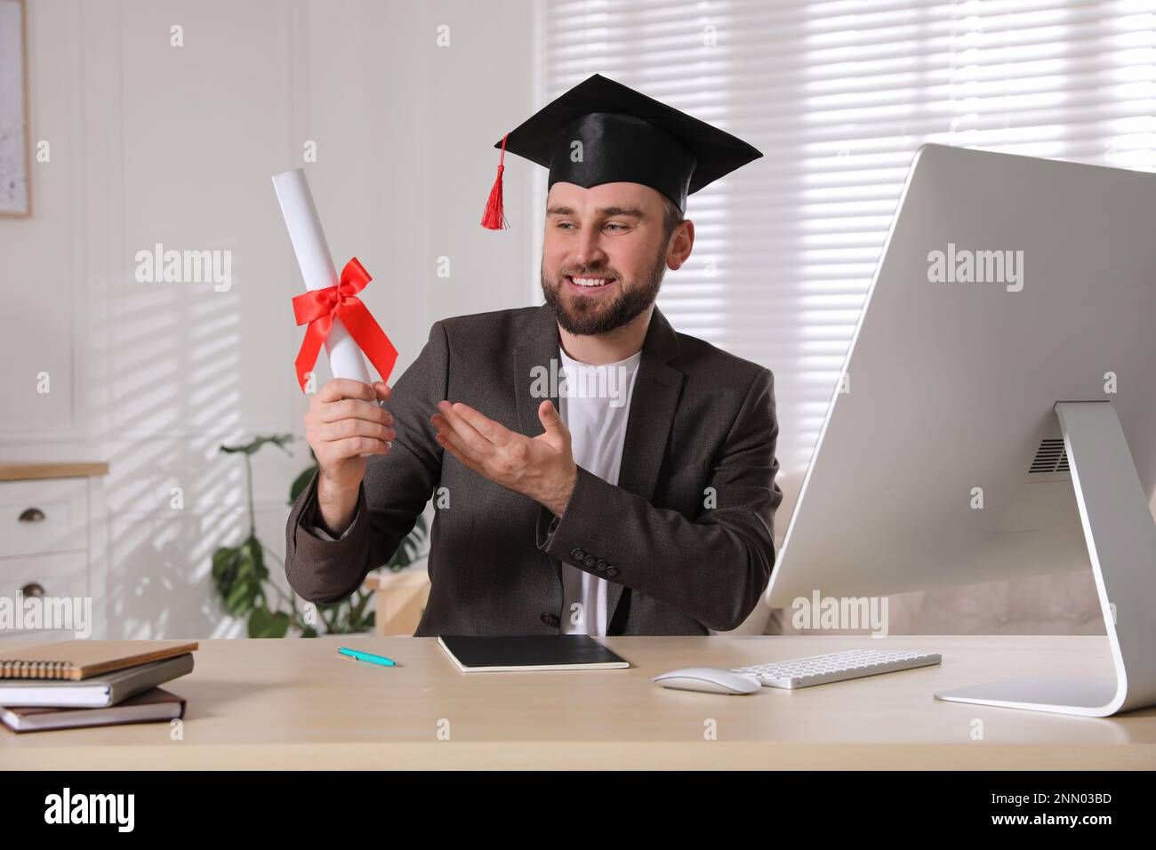 Happy student with graduation hat and diploma at workplace in office ...
