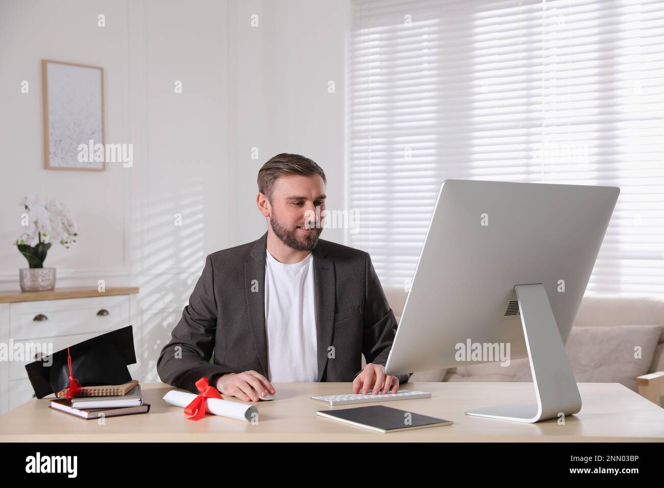 Happy student with graduation hat and diploma at workplace in office ...