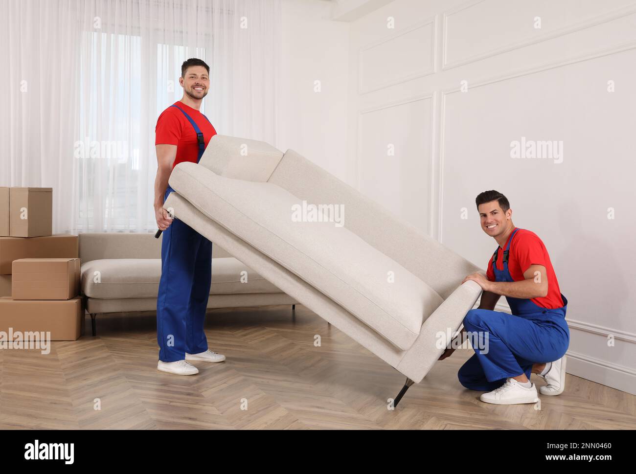 Professional movers carrying sofa in new house Stock Photo - Alamy