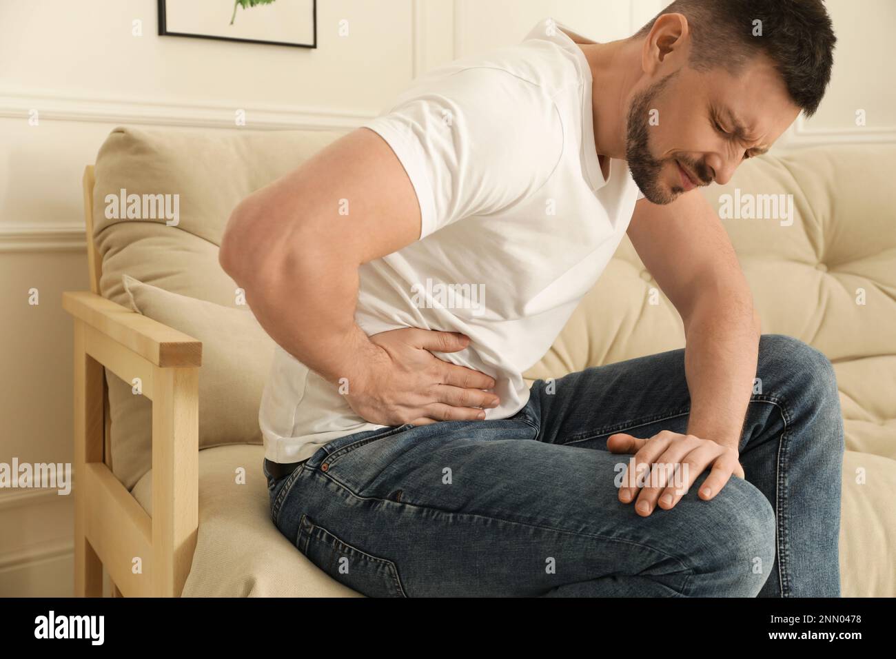 Man suffering from pain in lower right abdomen on sofa at home. Acute ...
