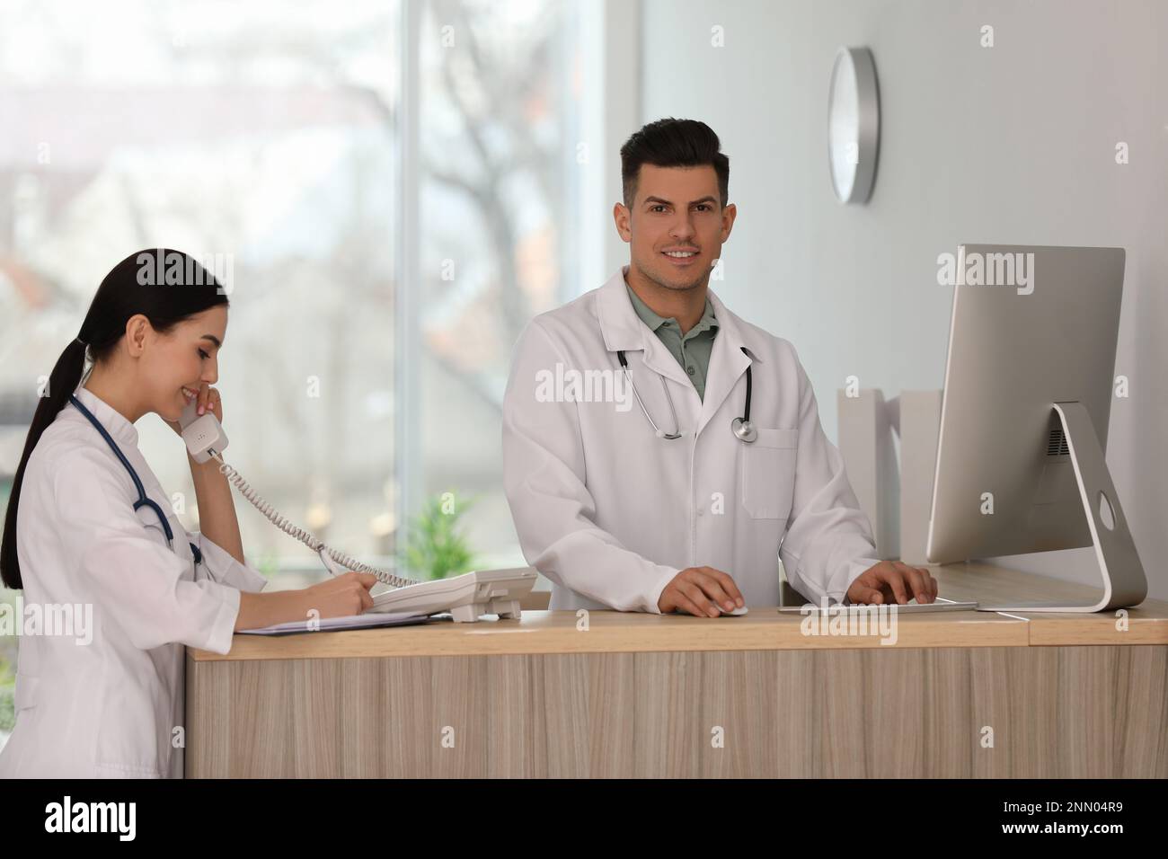 Receptionist and doctor working at countertop in hospital Stock Photo ...