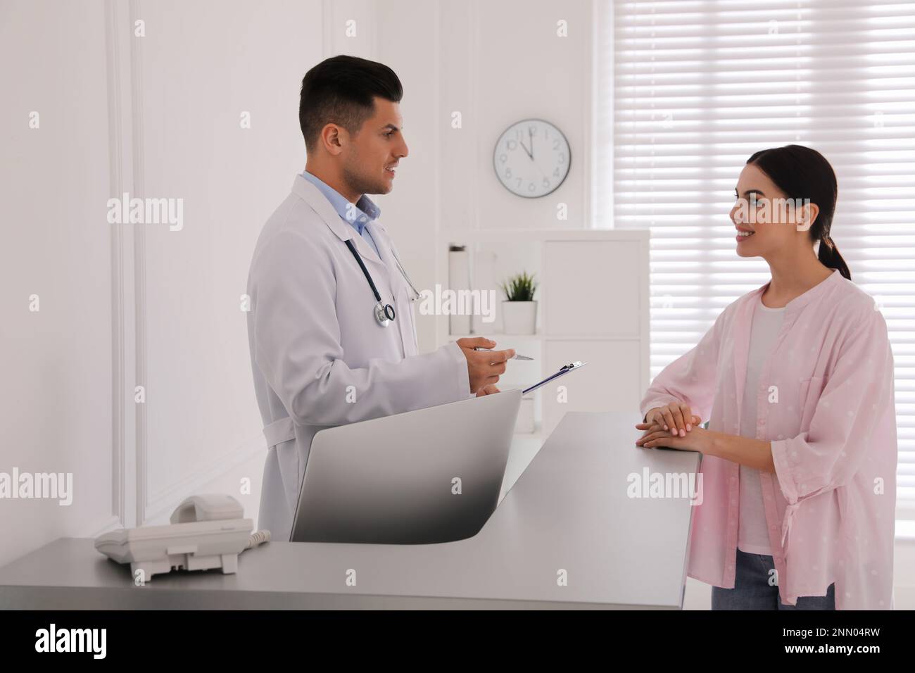 Doctor working with patient at reception in hospital Stock Photo - Alamy