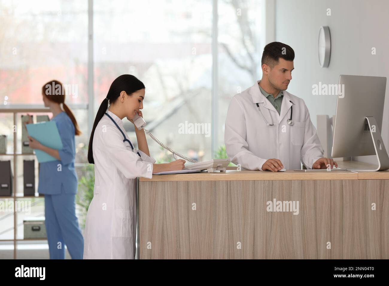 Receptionist and doctor working at countertop in hospital Stock Photo ...