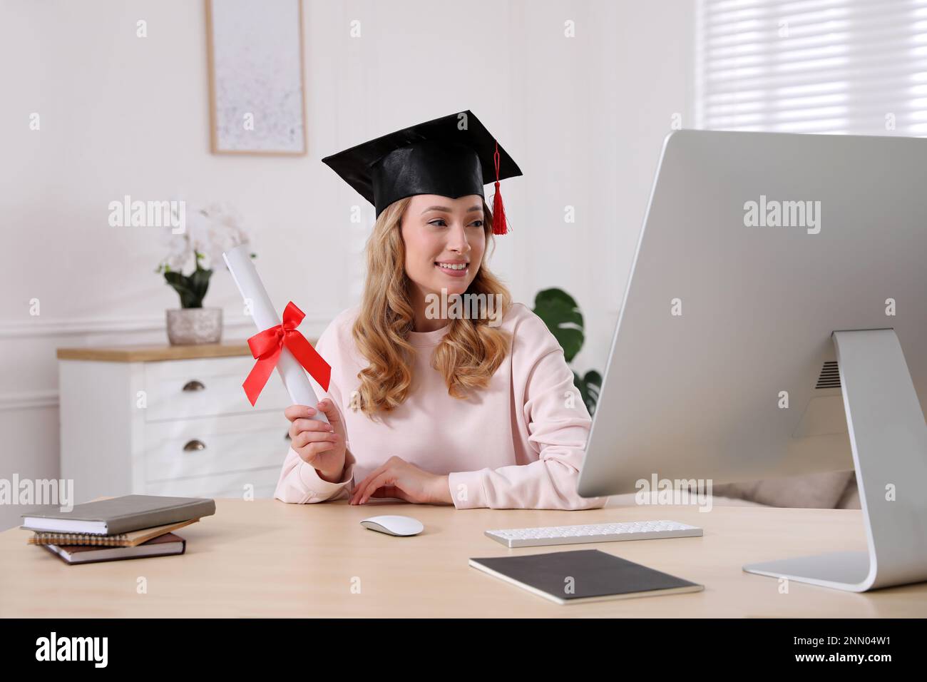 Happy student with graduation hat and diploma at workplace in office ...