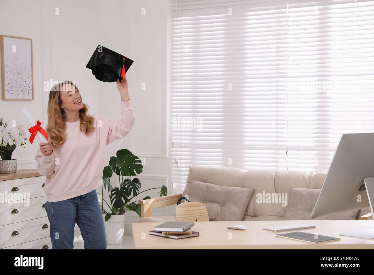 Happy student with graduation hat and diploma at workplace in office ...