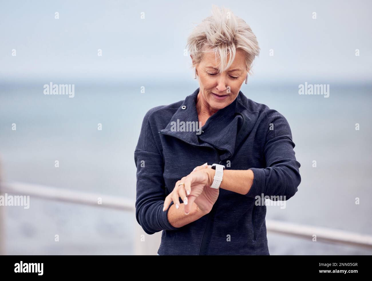 Smart watch, senior woman and fitness outdoor at beach promenade ...
