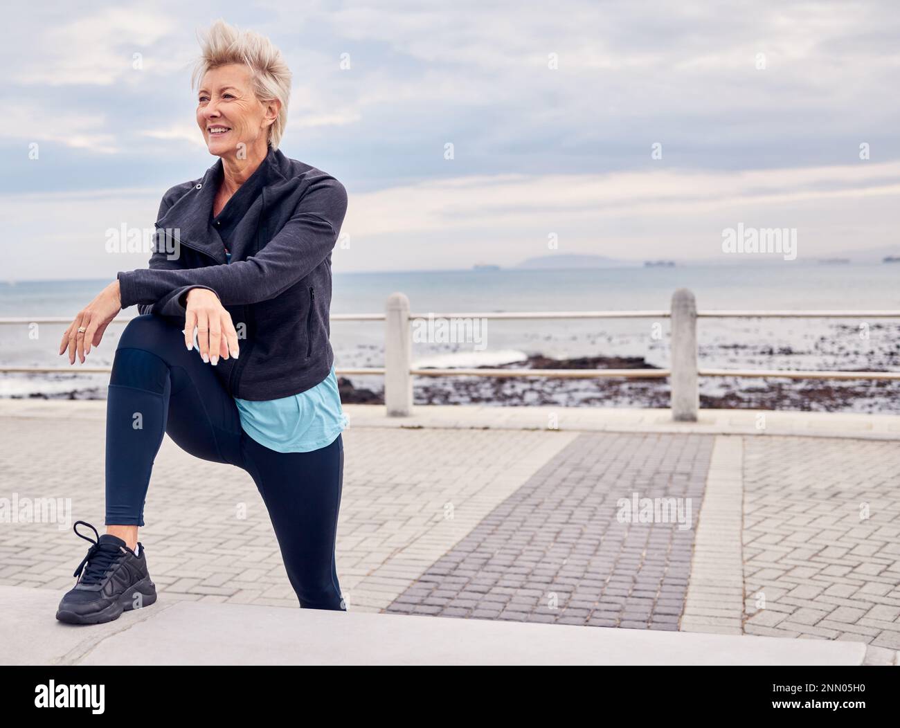 Senior woman, fitness and stretching at beach sidewalk for energy ...