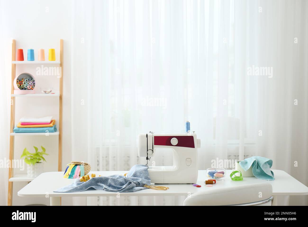 Modern sewing machine, fabric and accessories on table indoors Stock ...