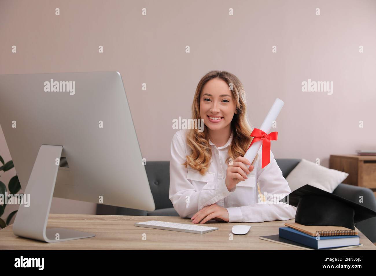Happy student with graduation hat and diploma at workplace in office ...