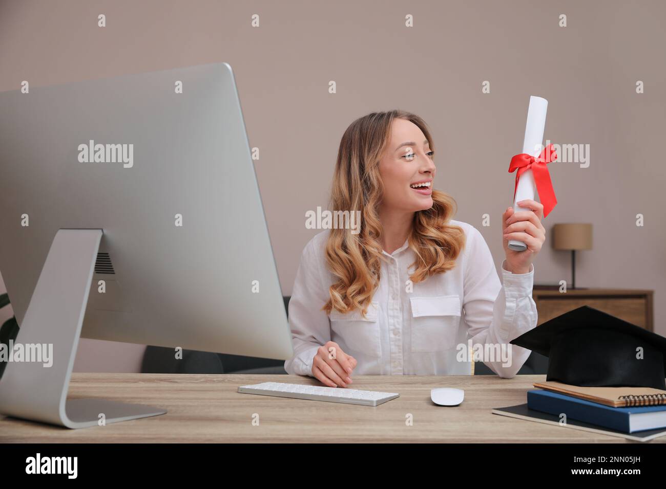 Happy student with graduation hat and diploma at workplace in office ...