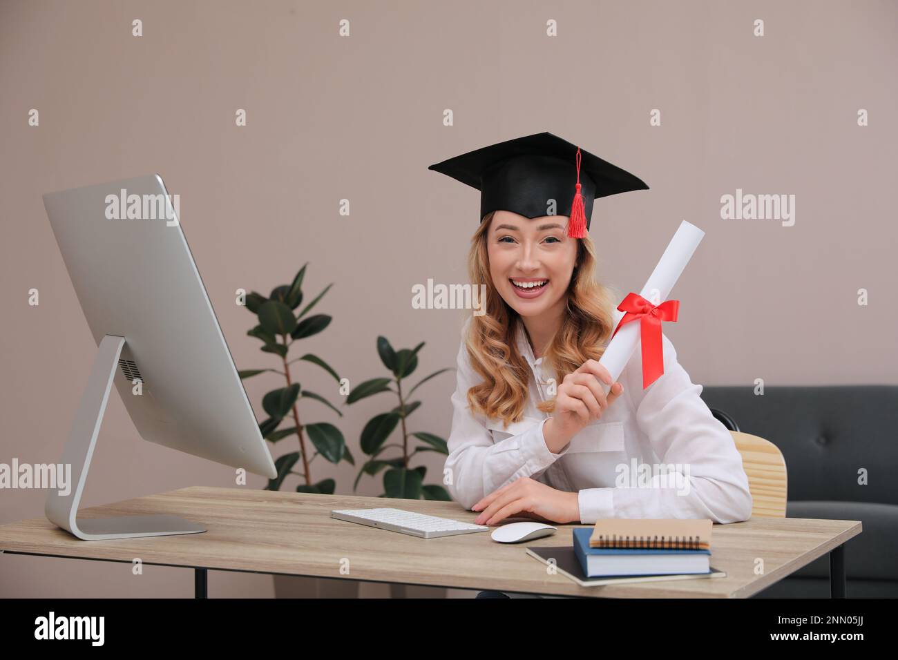 Happy student with graduation hat and diploma at workplace in office ...