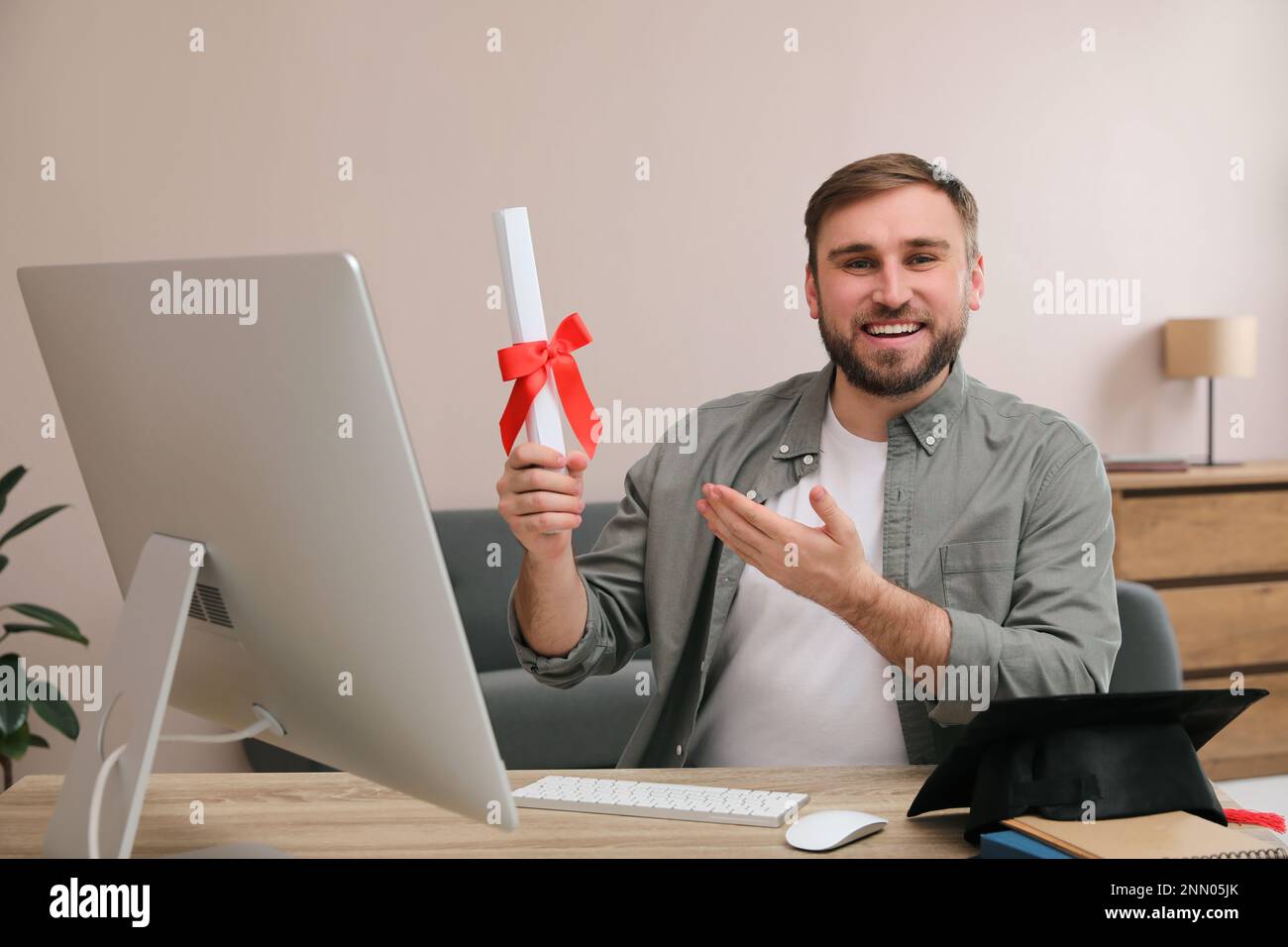 Happy student with graduation hat and diploma at workplace in office ...