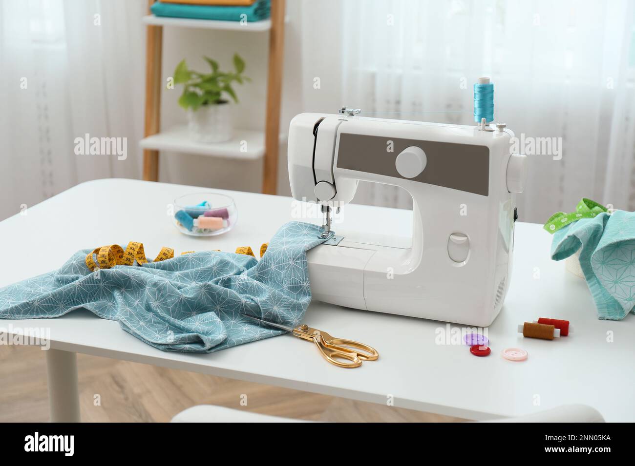 Modern sewing machine, fabric and accessories on table indoors Stock ...