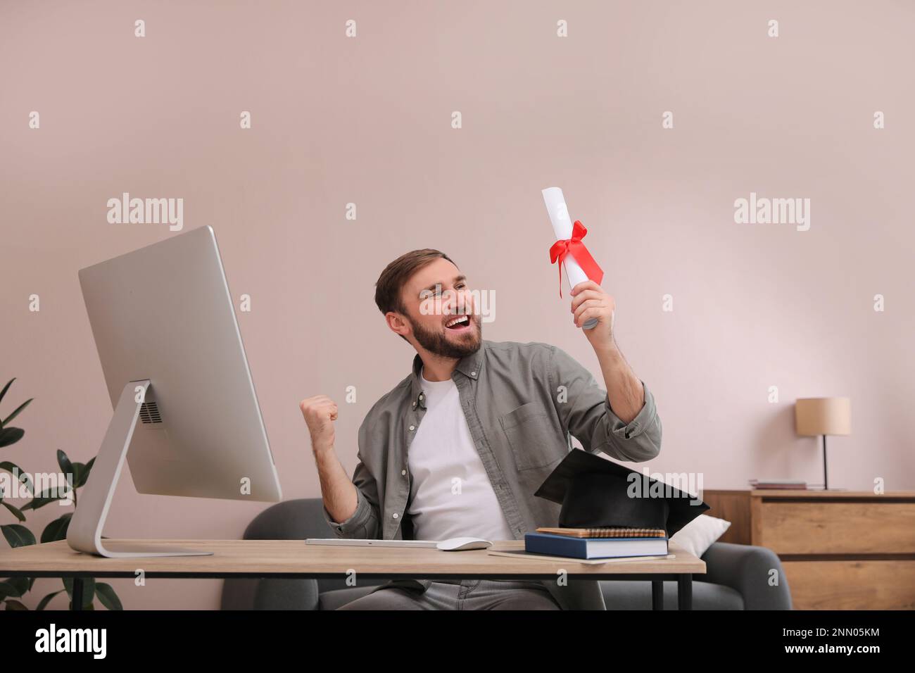 Happy student with graduation hat and diploma at workplace in office ...