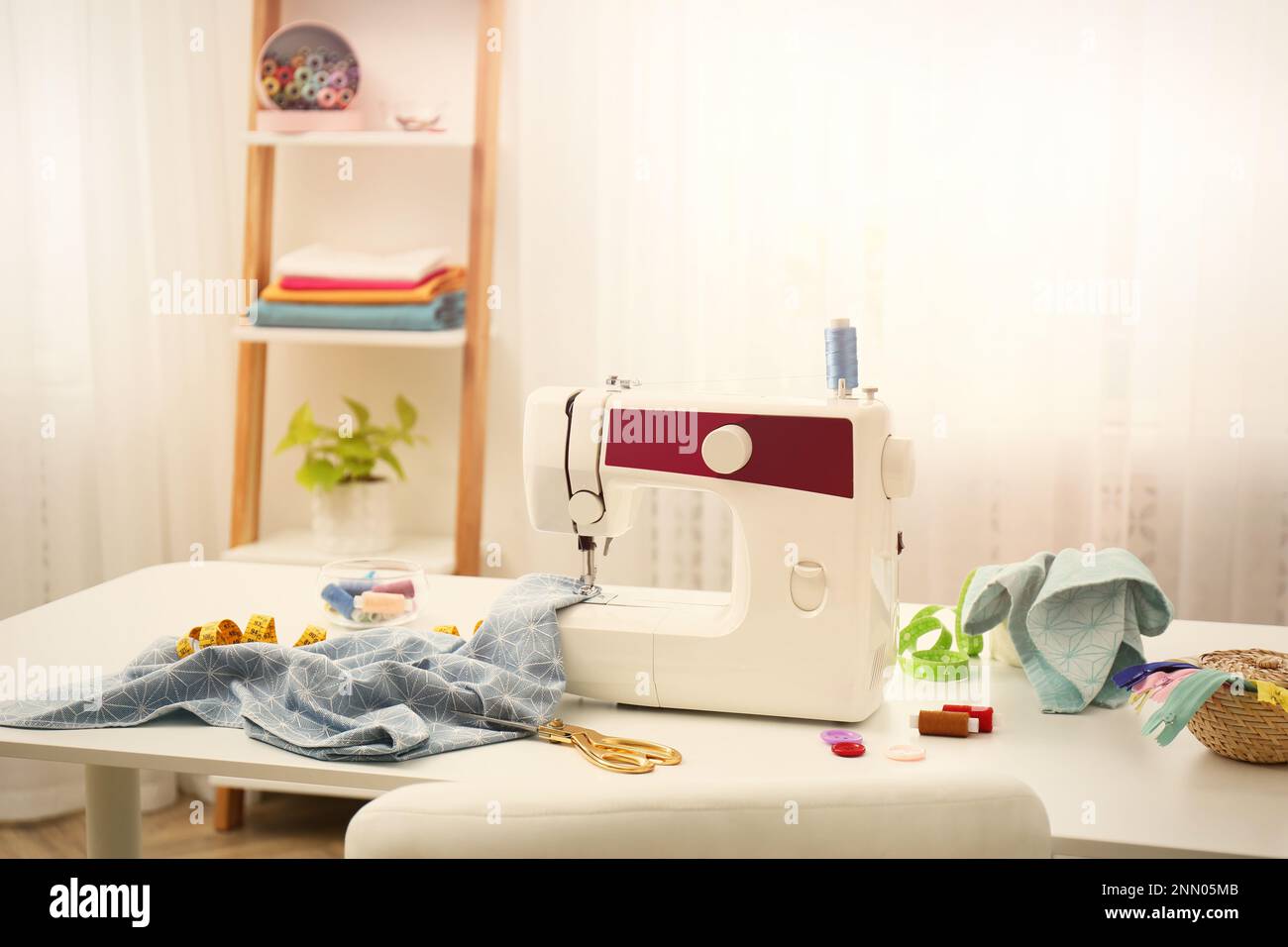 Modern sewing machine, fabric and accessories on table indoors Stock ...