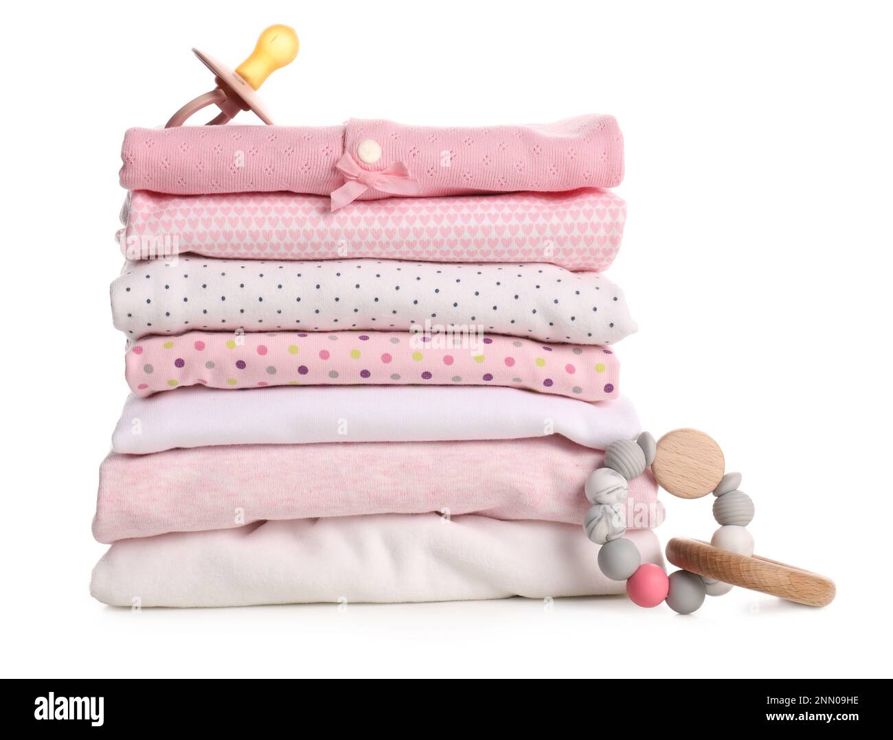 Stack of baby girl's clothes, pacifier and rattle on white background ...
