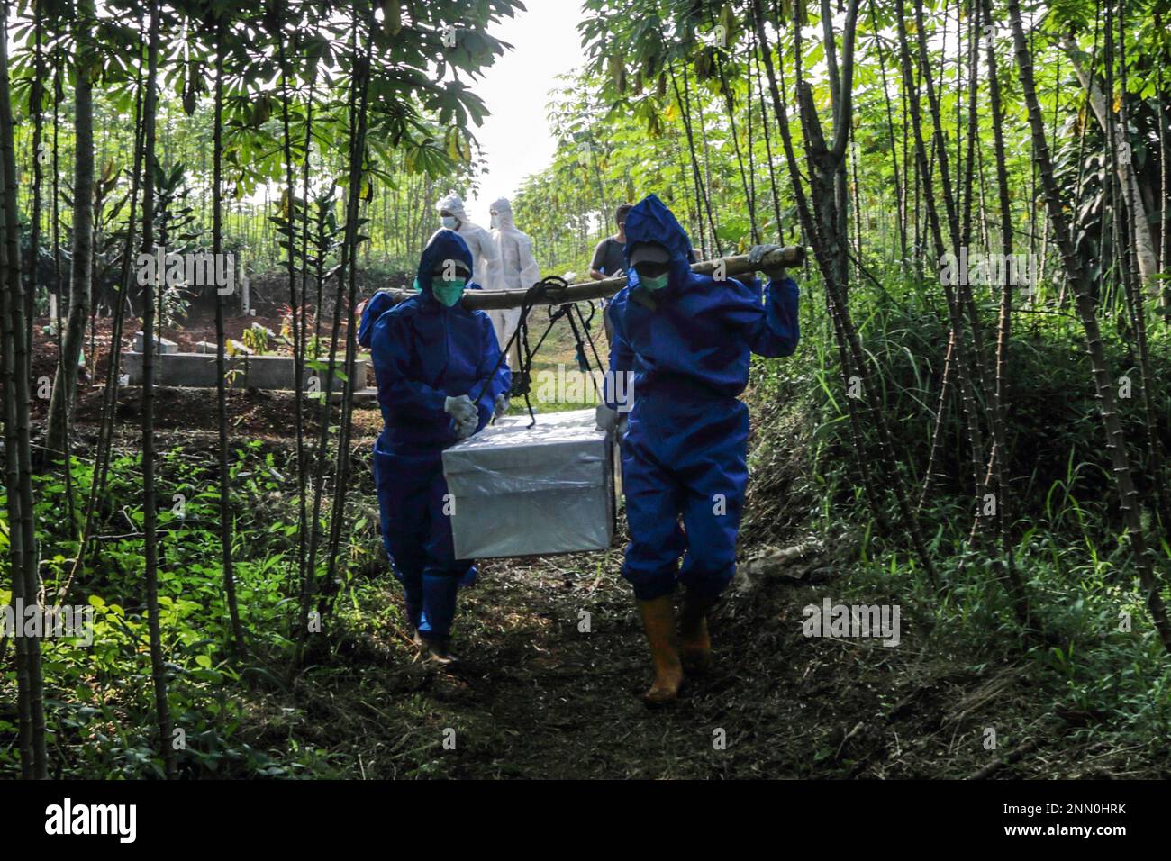Funeral workers wearing personal protective equipment carry a coffin of ...