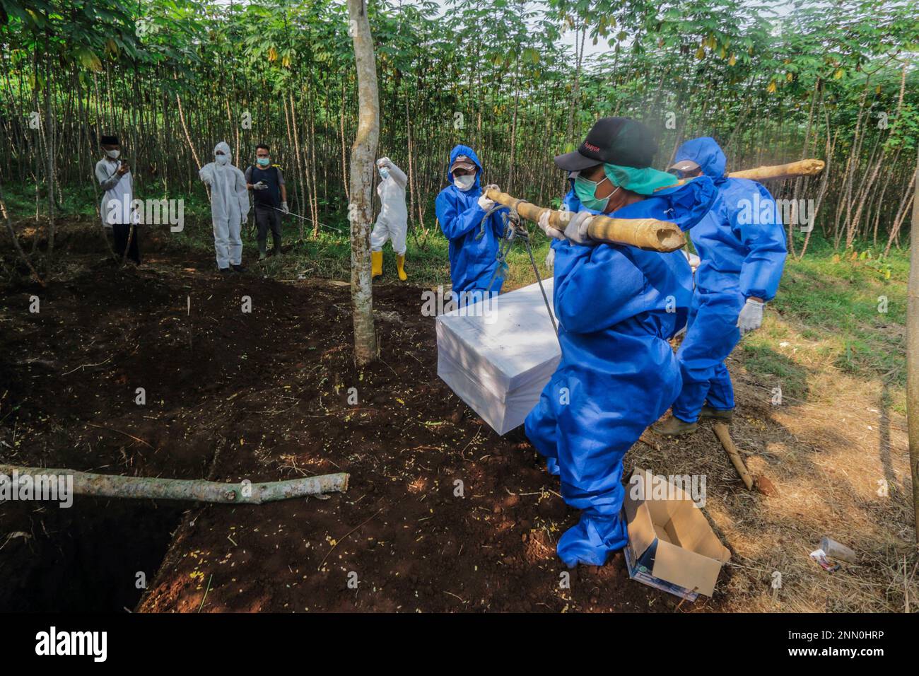 Funeral workers wearing personal protective equipment carry a coffin of ...