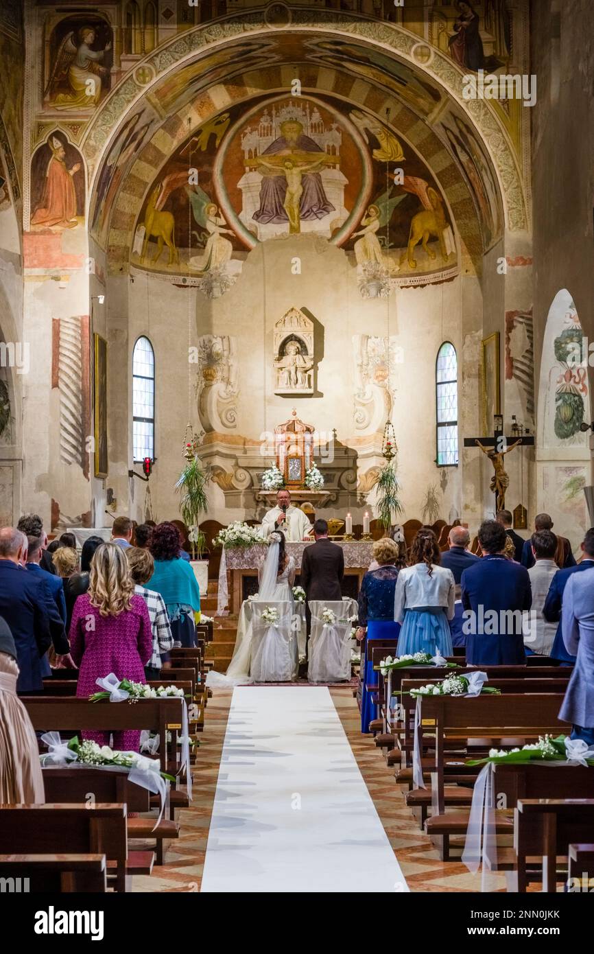 Wedding ceremony with priest, bride, groom and guests in a historic ...