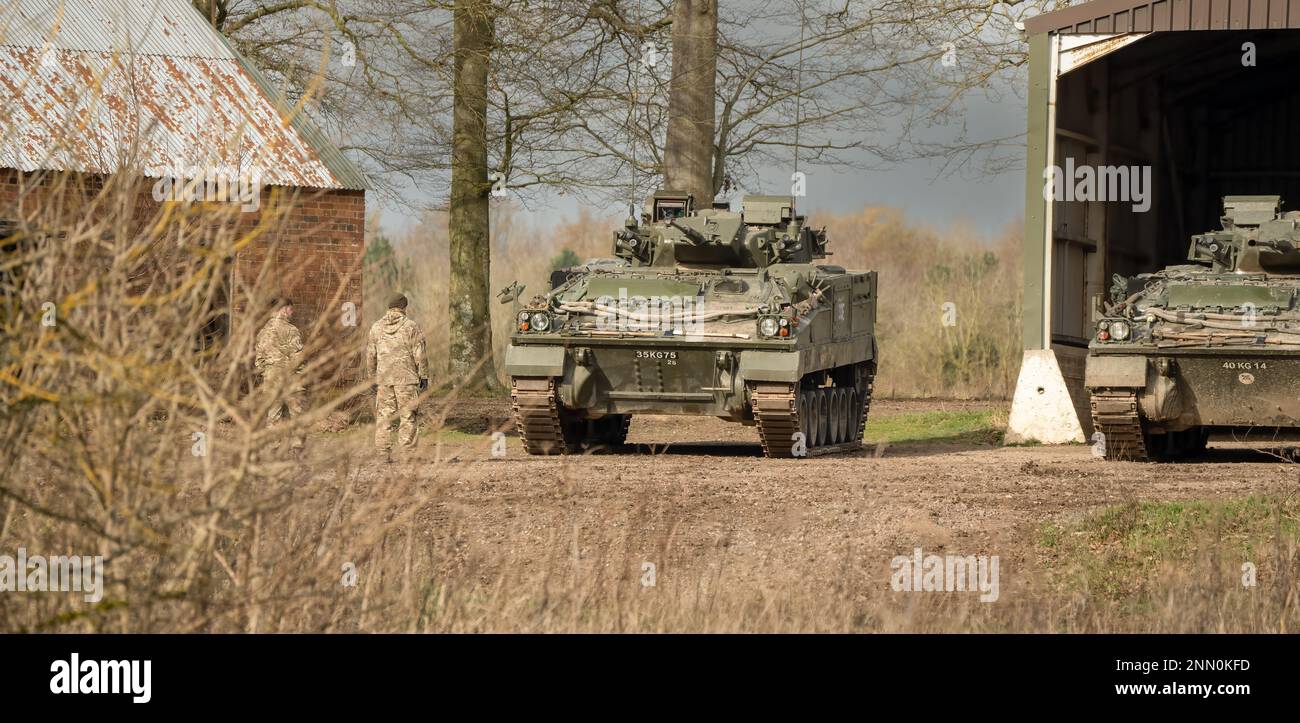 two soldiers stand in front of Warrior FV510 Infantry Fighting Vehicles ...
