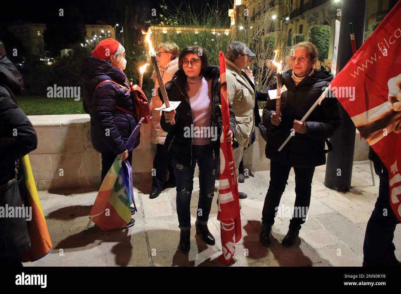 People with flags of Peace , protest signs and torches participate in a ...