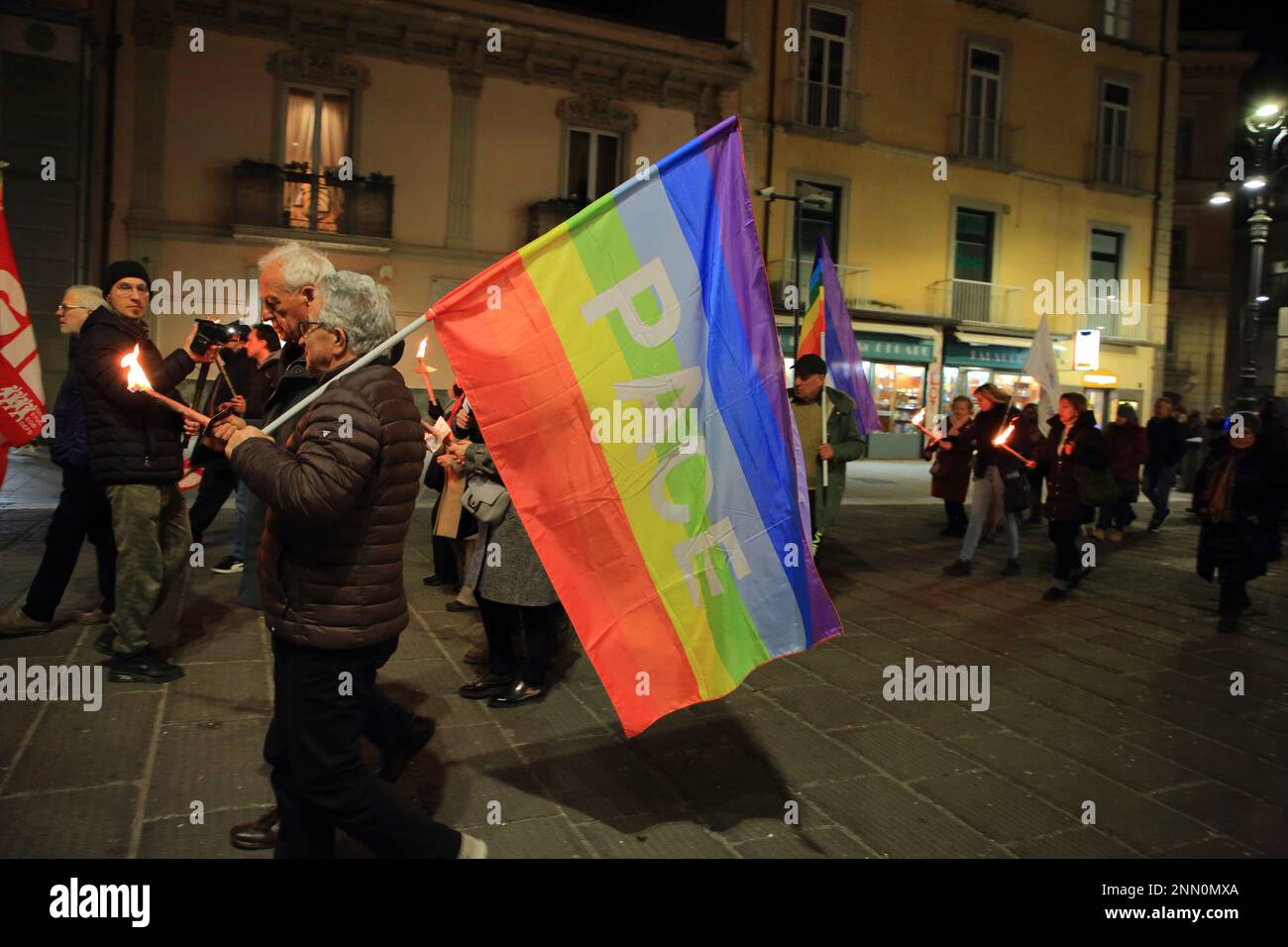 People with flags of Peace , protest signs and torches participate in a ...