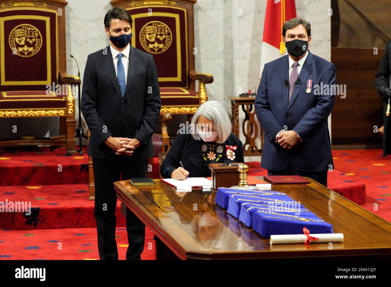 Mary Simon signs documents as Canadian Prime Minister Justin Trudeau, left, looks on after she ...
