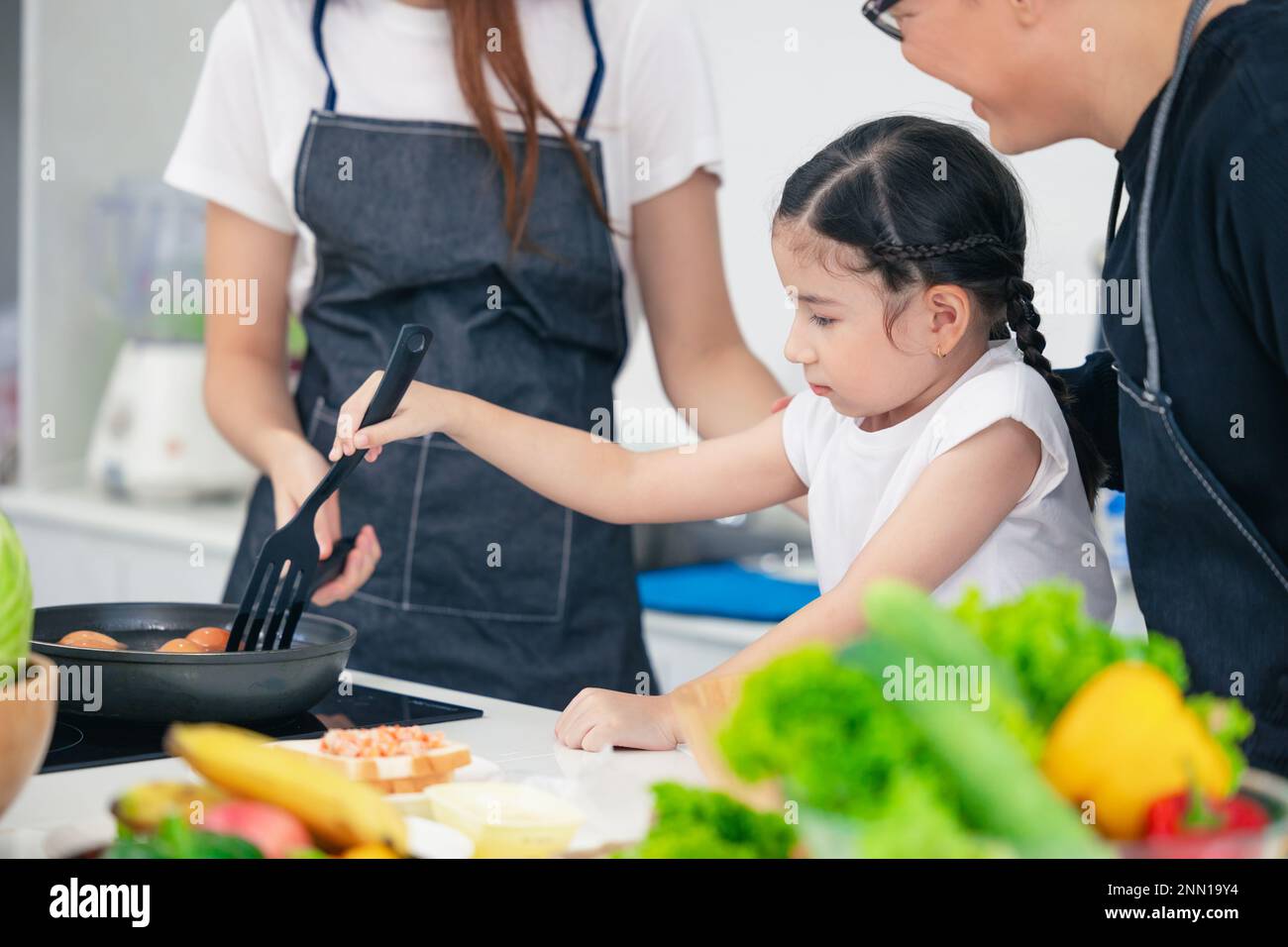 Child playing cook food with father and mother at home kitchen. Asian ...