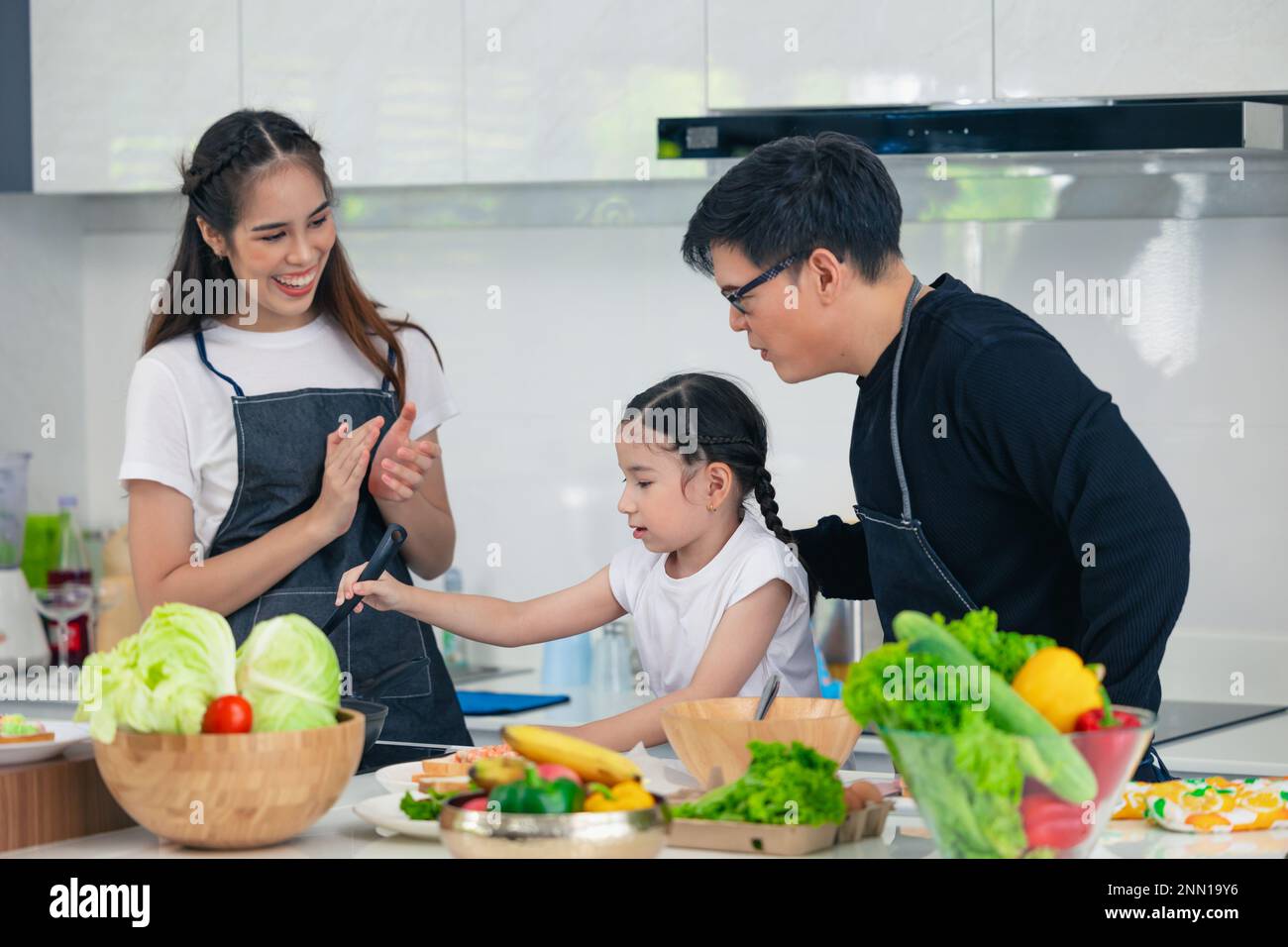 Child playing cook food with father and mother at home kitchen. Asian ...