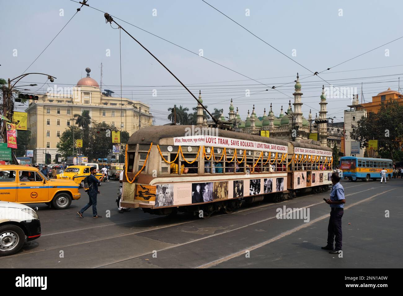 A decorated tram is crossing the busy city traffic. Various tram lovers ...
