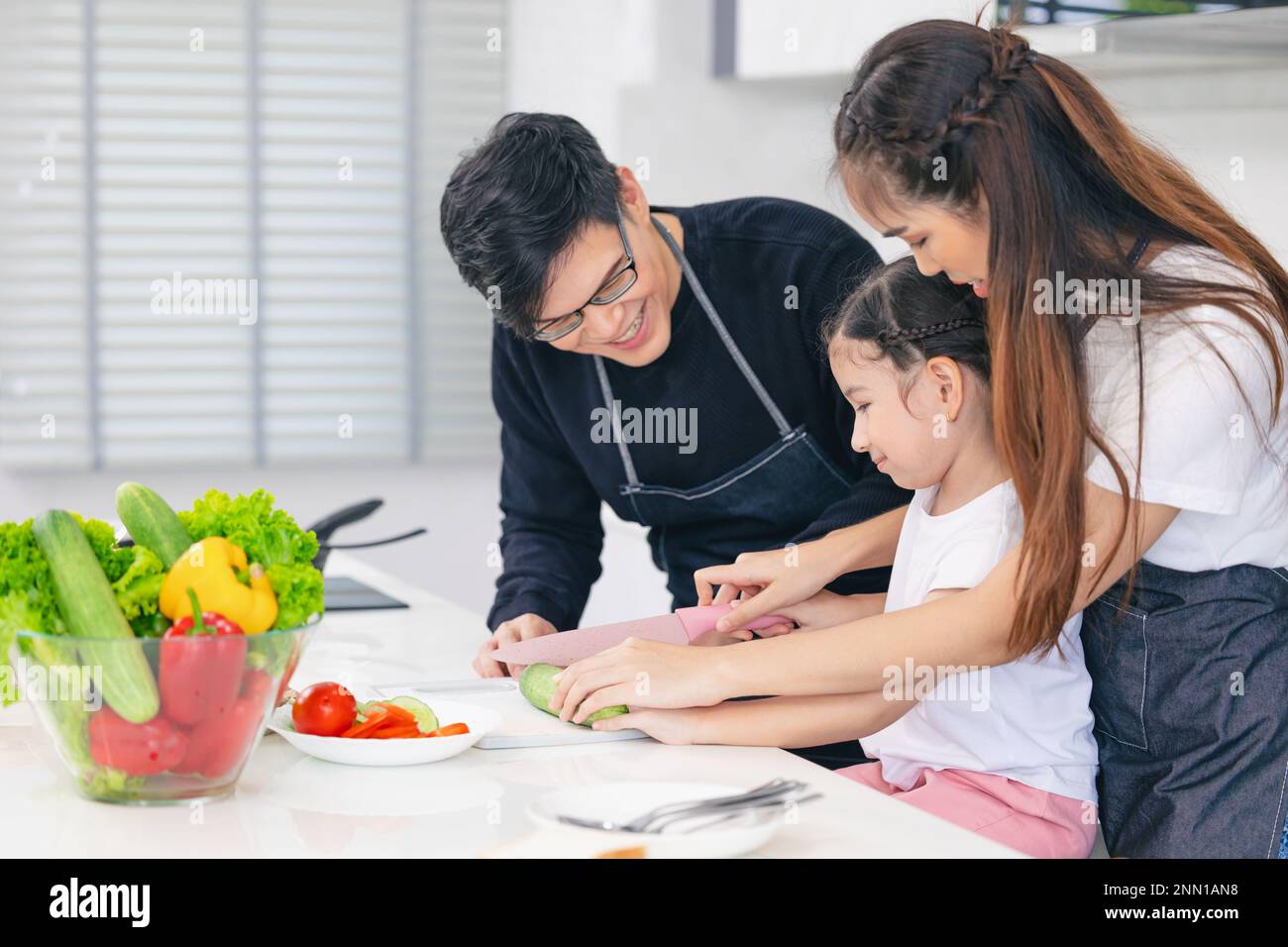 Child playing cook food with father and mother at home kitchen. Asian ...