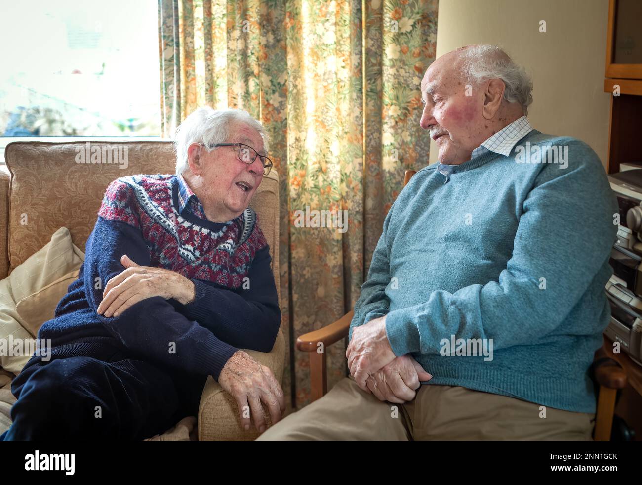 Two elderly men in their 90s who are lifelong friends sit and chat ...