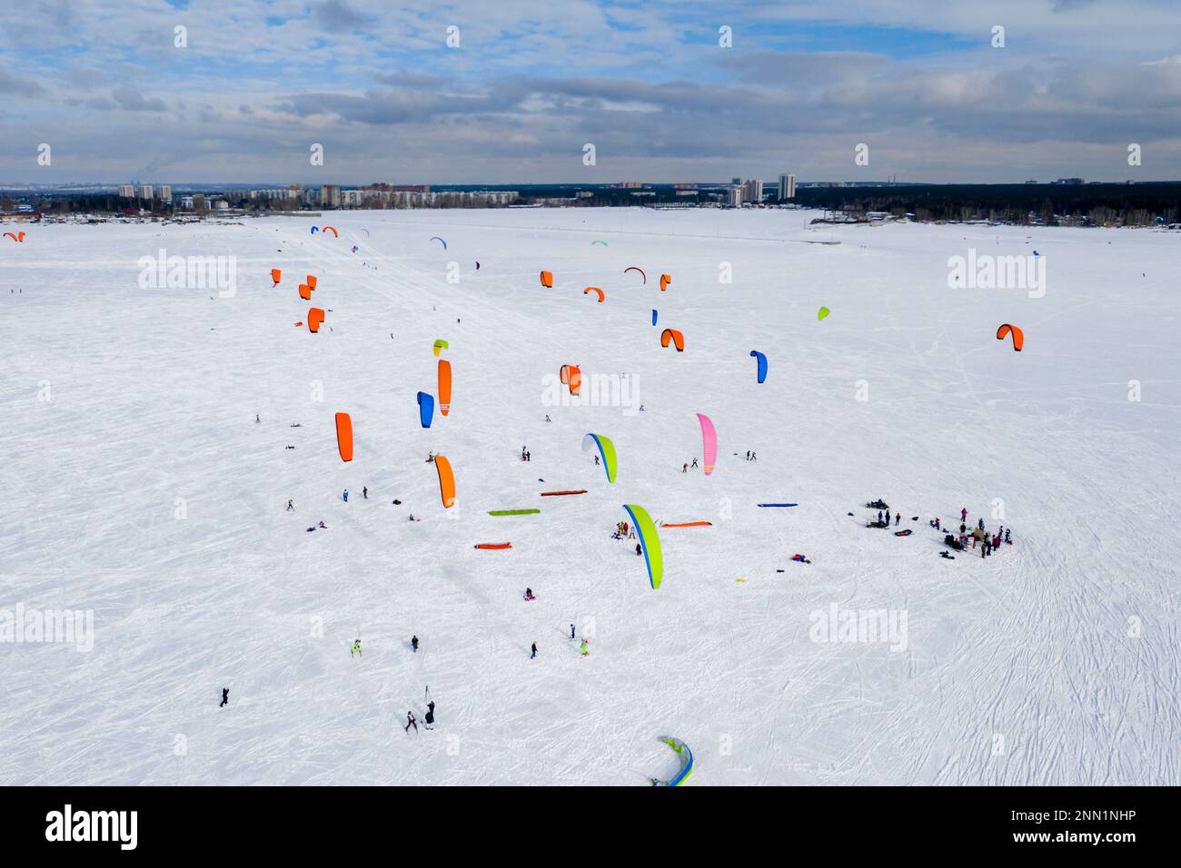 Aerial view of snowkiting competitions with colored parachutes on a ...