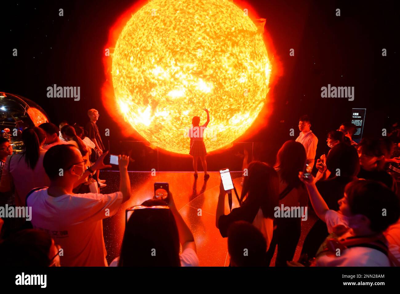 A girl poses in front of an image of the Sun at Shanghai Astrology ...