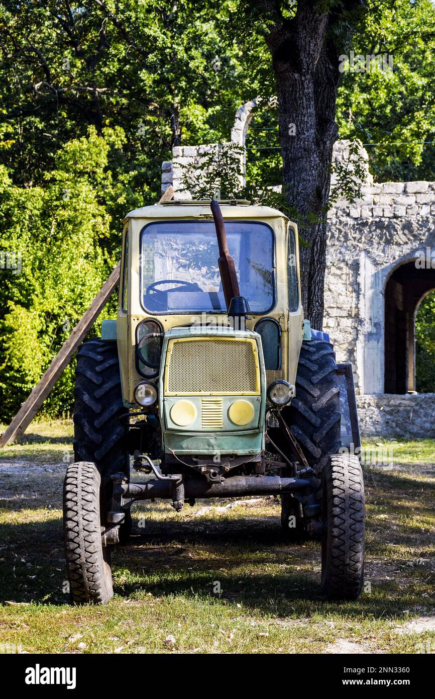 Old tractor with big wheels and rusty exhaust pipe. It stands on ...