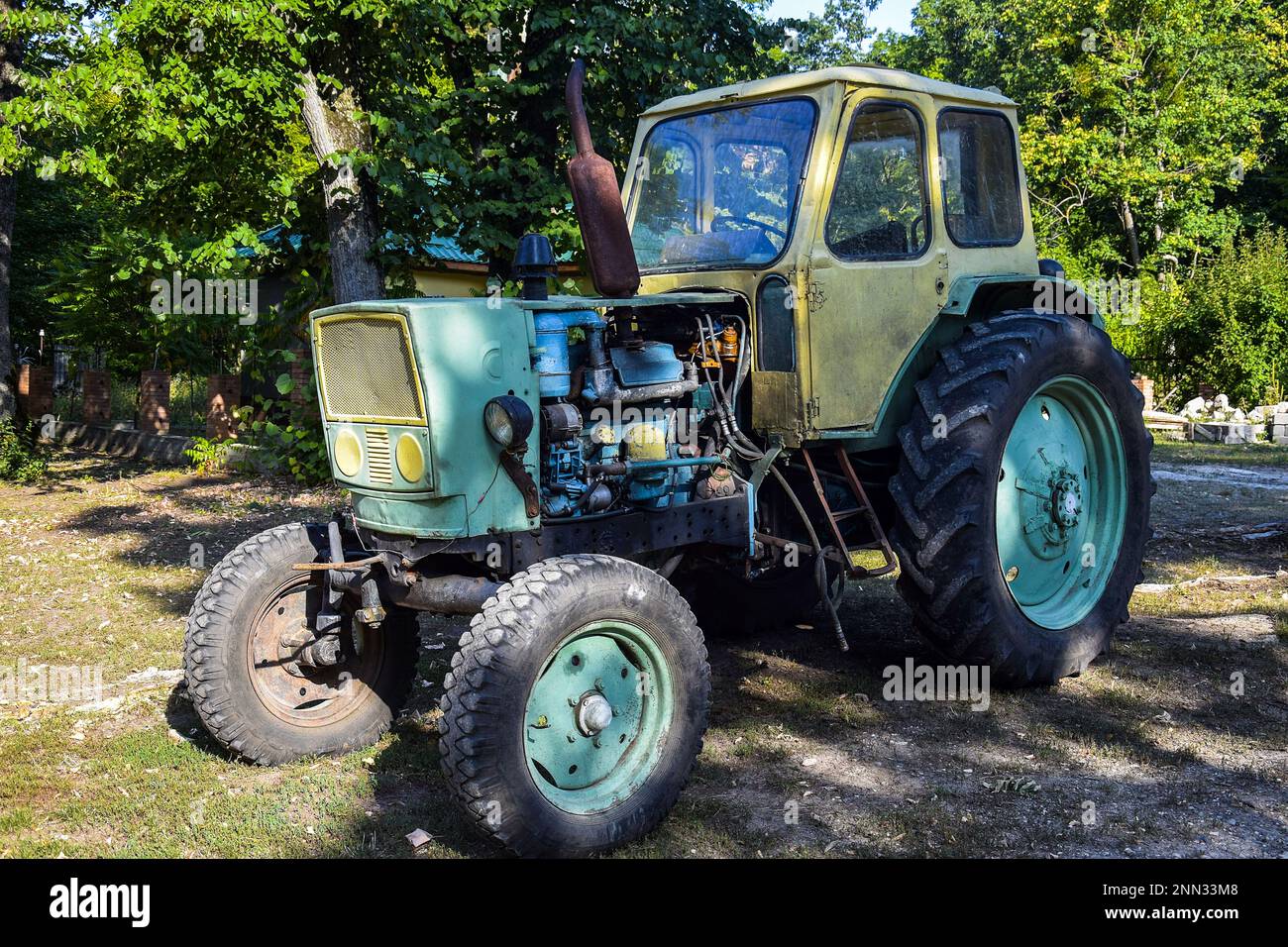 Old tractor with big wheels and rusty exhaust pipe. It stands on ...